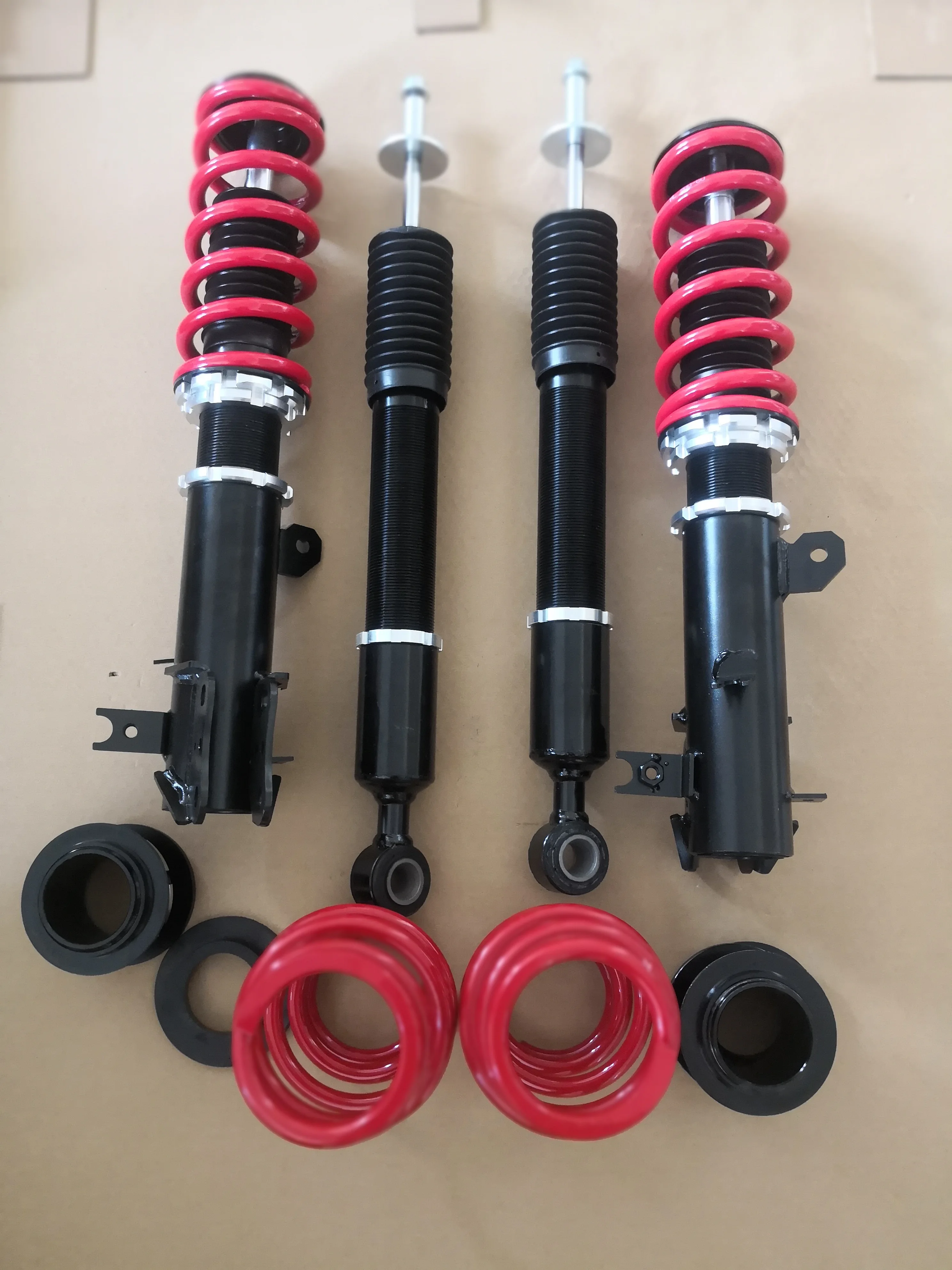 A set of three coilover suspension kits, likely for a Suzuki Swift, with red springs and black ...